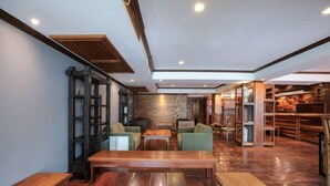 Um interior moderno com mesas e cadeiras de madeira, uma escada e uma parede com design em painéis de madeira.