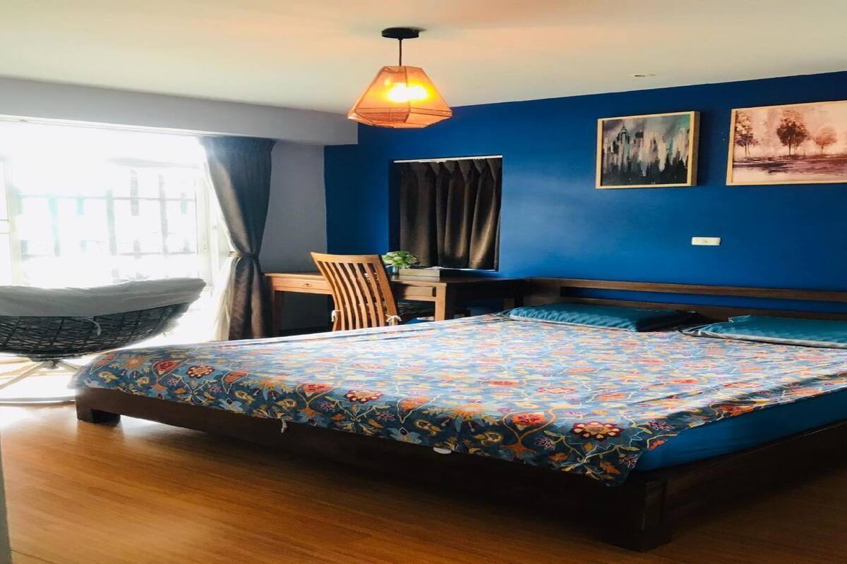 Quarto com cama, escrivaninha e duas pinturas na parede.