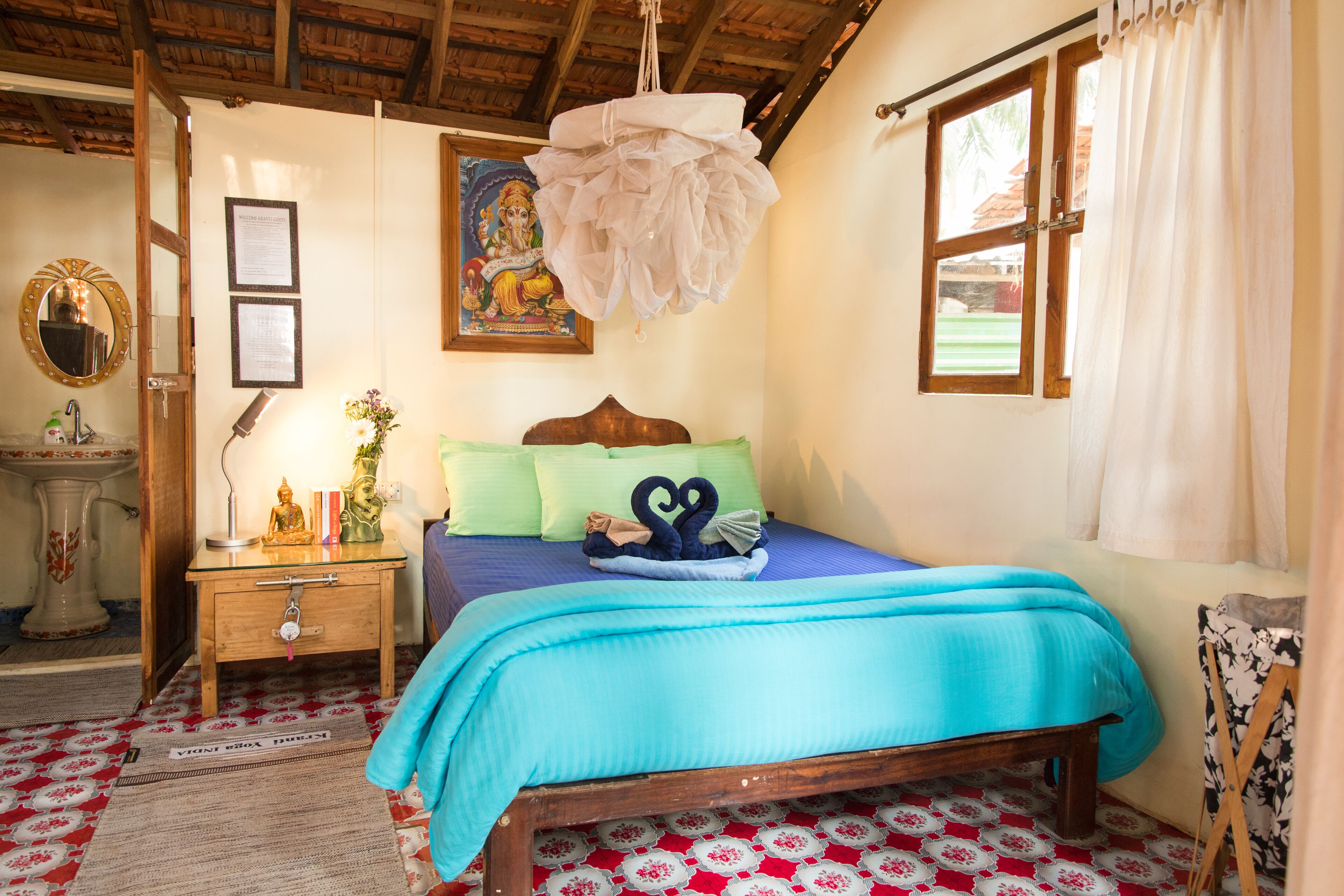 Quarto com cama, mesa de cabeceira, espelho, janela com cortinas e teto de madeira.