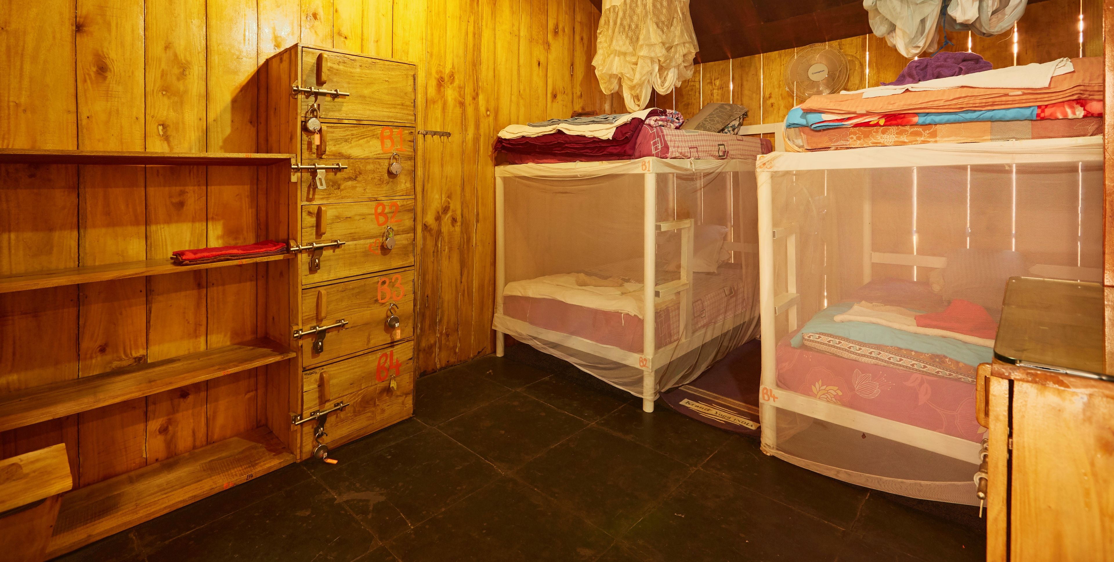 Quarto em dormitório para quatro pessoas, com paredes de madeira, guarda-roupa e beliches.