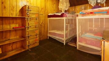 Quarto em dormitório para quatro pessoas, com paredes de madeira, guarda-roupa e beliches.