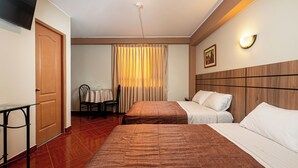 Quarto de hotel com duas camas, uma escrivaninha, uma cadeira, uma mesa e uma televisão.