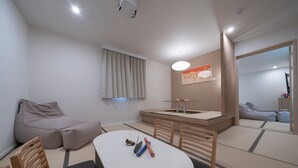 Quarto moderno e minimalista com piso de esteira de tatame, mesa de madeira baixa com almofadas, sofá e um espelho grande.