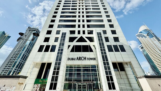 A Dubai Arch Tower com um design arquitetônico moderno, apresentando uma entrada notável e edifícios altos ao redor.
