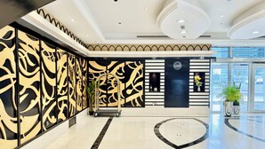 Um lobby moderno com parede estampada em padrão geométrico, um relógio central e um design de piso circular.