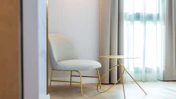 Quarto moderno com uma cadeira de cor clara e uma pequena mesa redonda com moldura dourada.