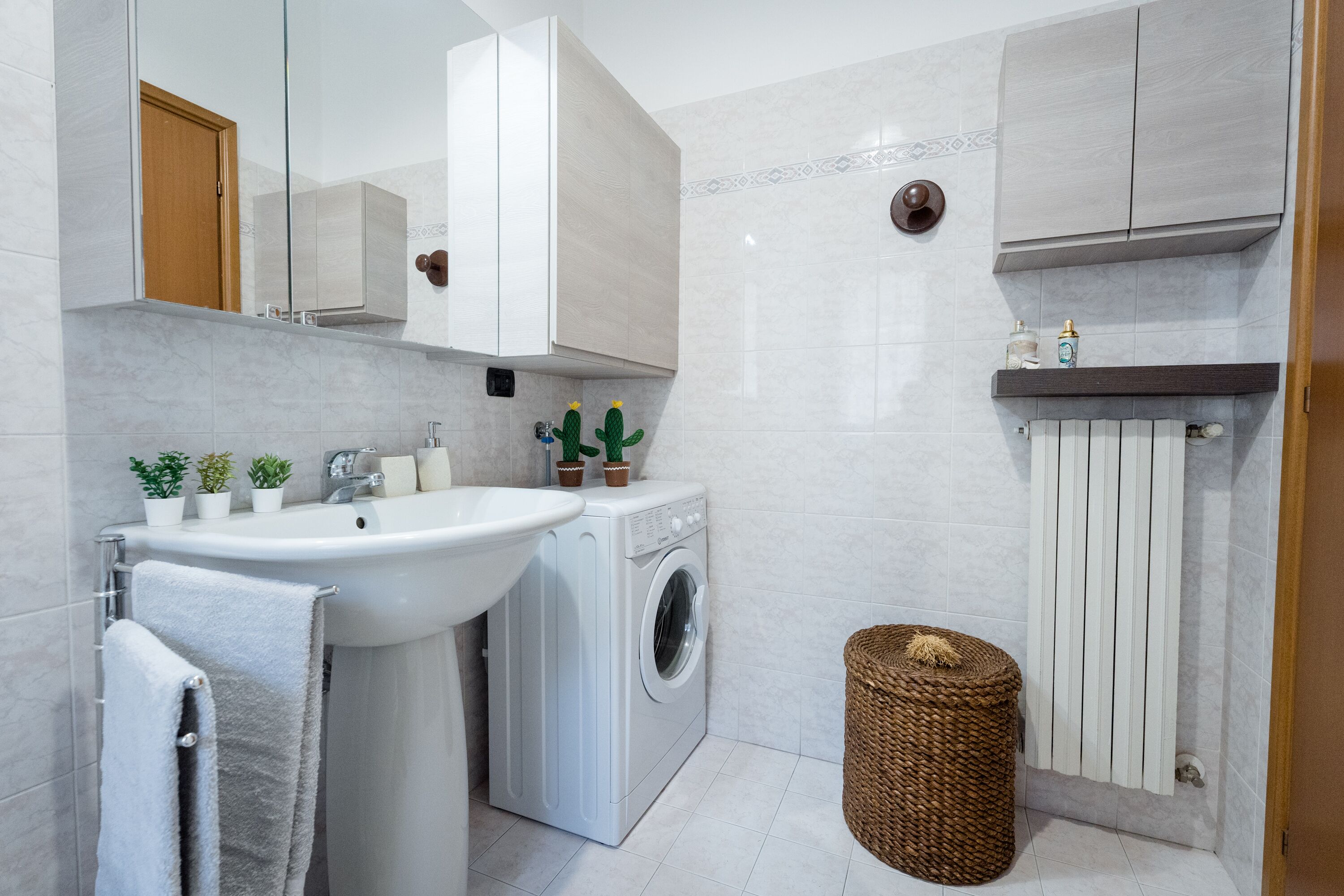 Uma casa de banho moderna com lavatório, máquina de lavar roupa e radiador.