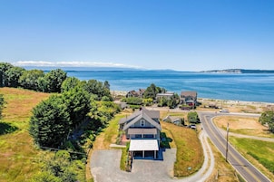 Uma área residencial costeira com casas, uma estrada e vista para o mar.