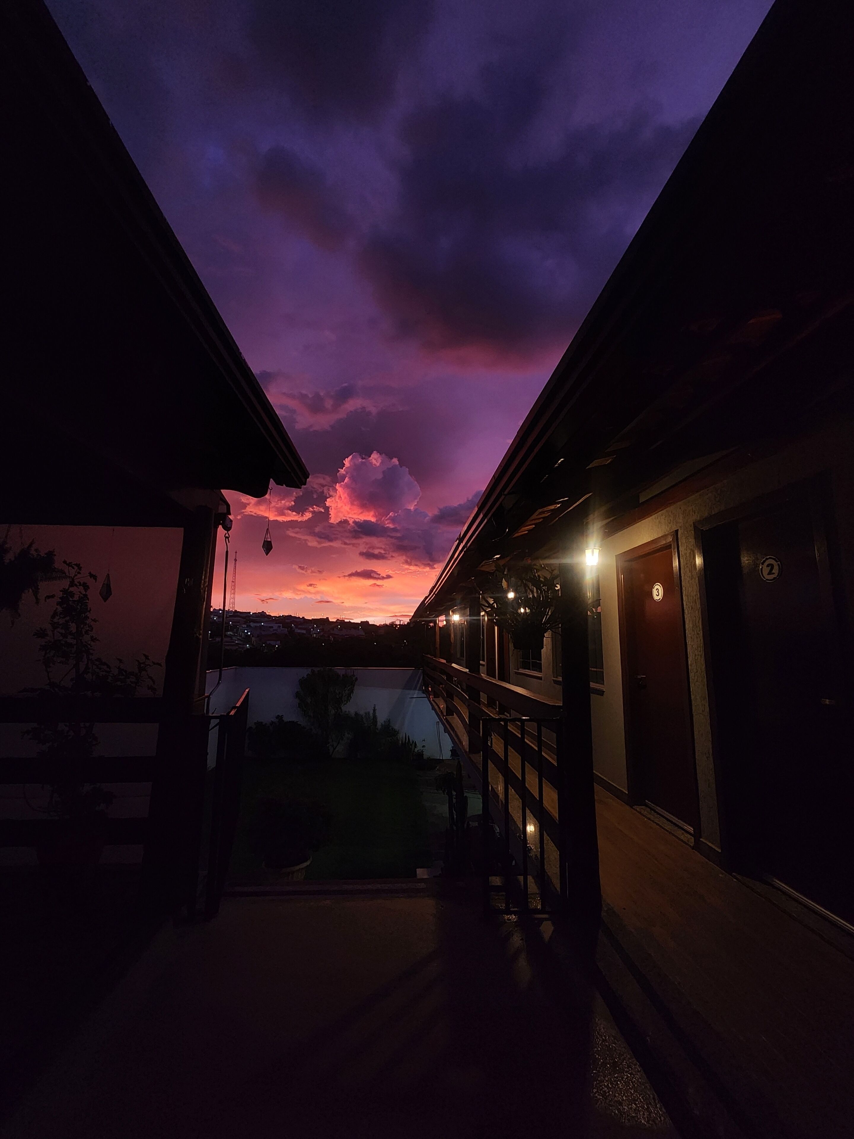 Um edifício com área externa coberta e vista para o céu ao entardecer.