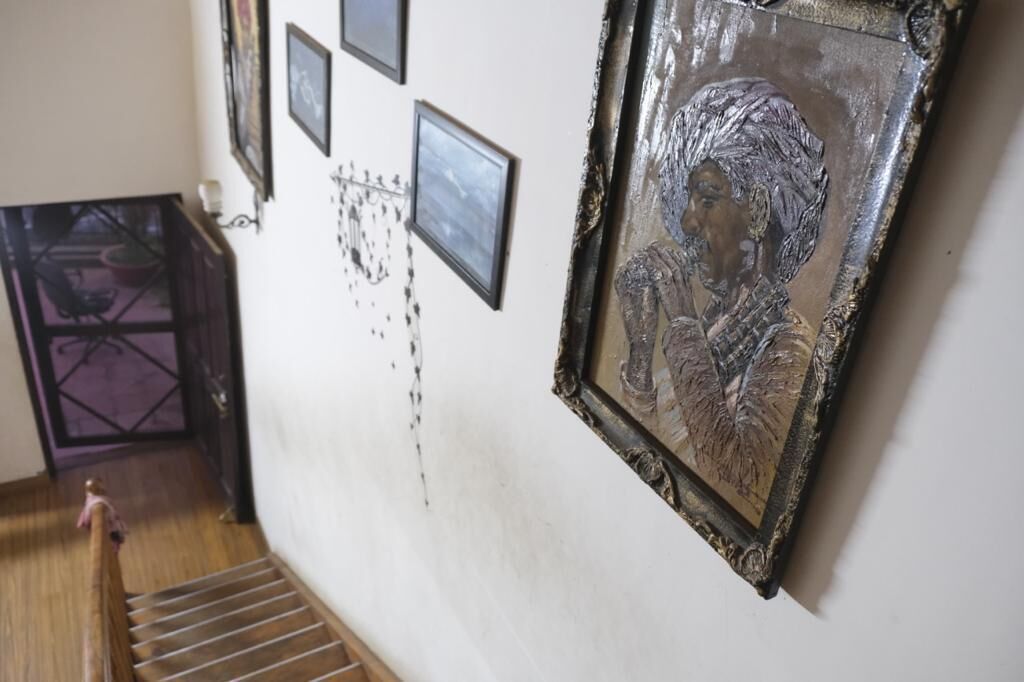 Uma escadaria com corrimão e parede com várias fotografias emolduradas.