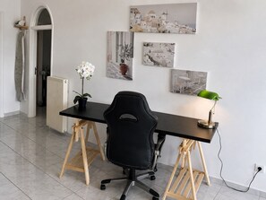 Um espaço de trabalho com uma cadeira de escritório preta, uma escrivaninha de madeira e um radiador.