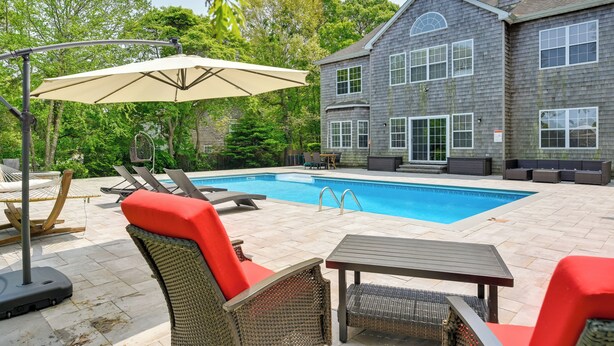 Um quintal com piscina, móveis de jardim e uma casa.