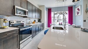 Uma cozinha moderna com eletrodomésticos de aço inoxidável, uma ilha central e vista para a área de refeições.