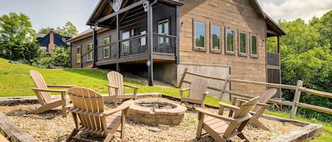 Uma cabana de madeira com varanda, lareira e cadeiras Adirondack.