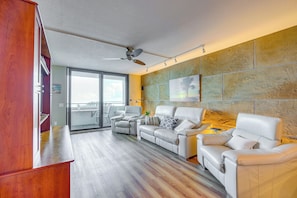 Uma sala de estar moderna com um sofá, um ventilador de teto e uma janela grande.