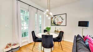 Uma área de refeições com uma mesa redonda, cadeiras pretas e um candelabro.
