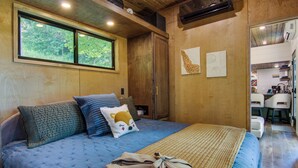Quarto com uma cama grande, uma janela e teto de madeira.