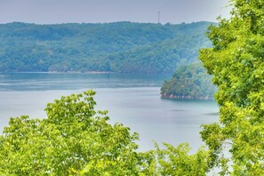 Vista de um lago com uma colina arborizada ao fundo.