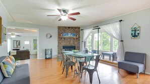 Uma sala de estar ampla com mesa de jantar, sofá cinza e lareira com o letreiro "SUN FUN".