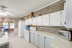 Cozinha moderna com armários brancos, forno embutido, micro-ondas e ventoinha no teto.