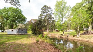 Um camping com uma pequena cabana, um lago e árvores ao redor.