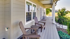 Varanda coberta com cadeiras Adirondack, uma mesa pequena e um letreiro com a palavra 'TOUR'.