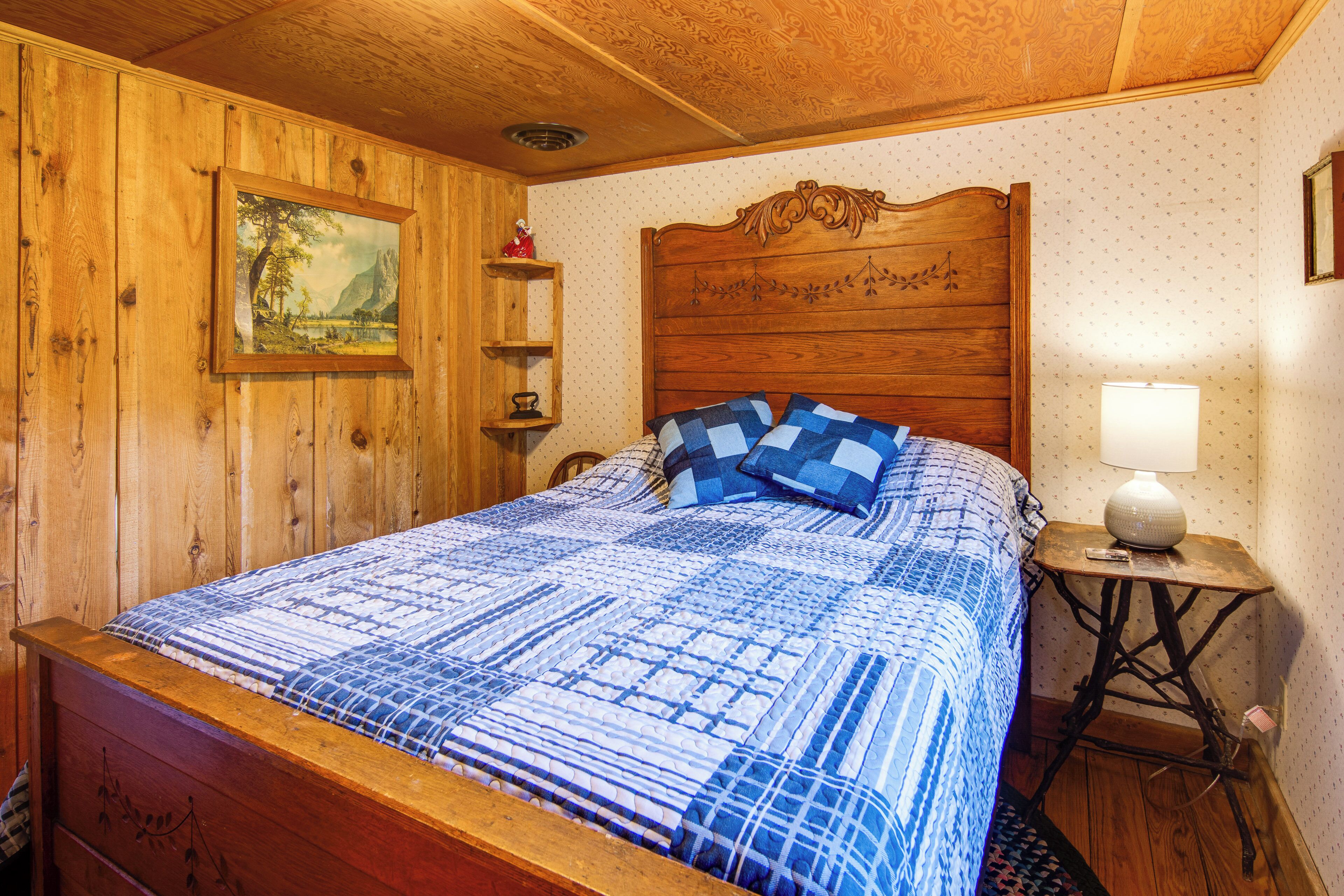 Um quarto com painéis de madeira, uma cama, uma mesa de cabeceira, um abajur e um quadro na parede.