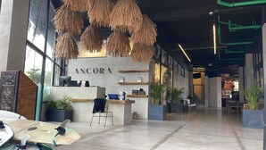 Uma área de recepção moderna com um letreiro 'ANCORA', um balcão de atendimento e área de estar.