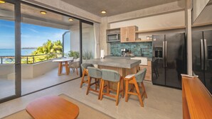 Cozinha moderna com uma bancada grande, banquetas e vista para o oceano.
