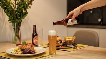 Uma mesa de jantar com um prato de comida, um copo de cerveja e uma garrafa sendo servida no copo.