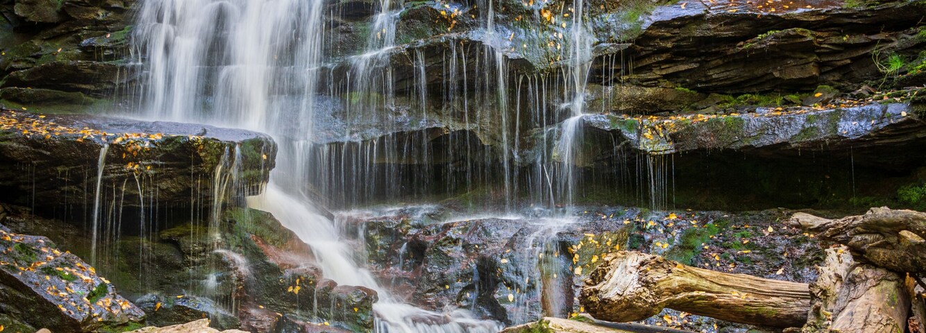 Uma cascata em vários níveis, rodeada por pedras e vegetação.