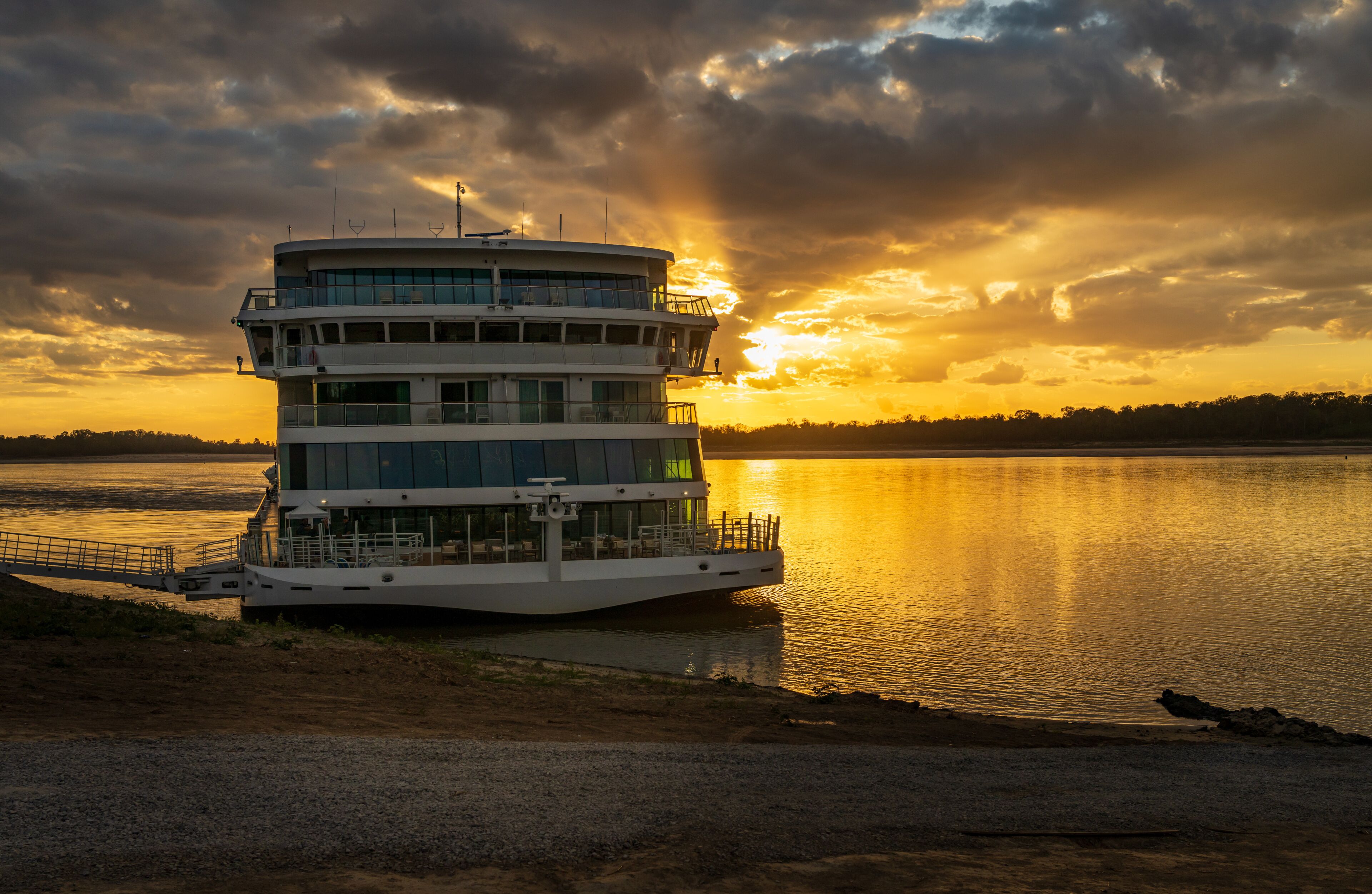 Um edifício com vários andares à beira de um rio calmo ao pôr do sol.