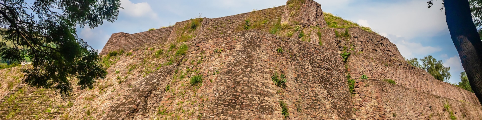Estrutura de pedra antiga com um muro íngreme em terraços e topo plano.