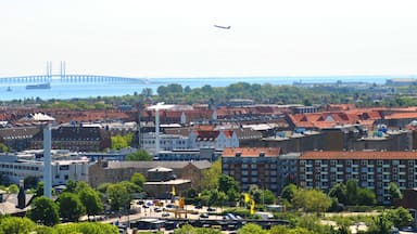 Paisagem urbana com uma ponte destacada ao fundo, mistura de edifícios residenciais e comerciais, e céu claro.