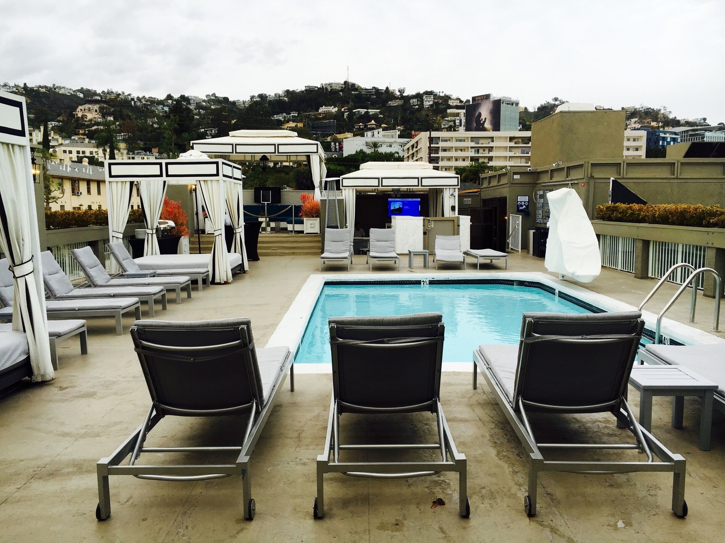 Piscina no terraço com espreguiçadeiras e vista para o horizonte urbano.