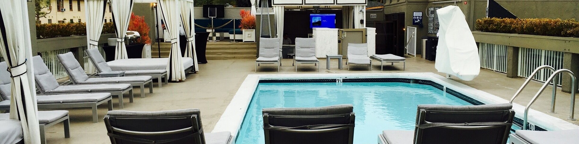 Piscina no terraço com espreguiçadeiras e vista para o horizonte urbano.