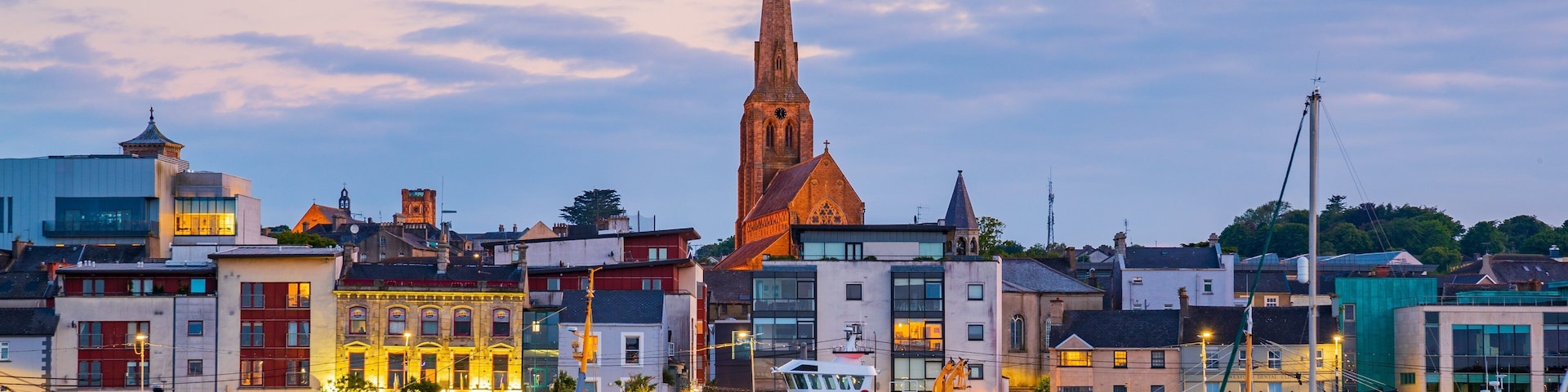 Um porto com barcos, uma torre de igreja e edifícios.