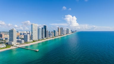 Paisagem costeira urbana com edifícios altos, uma praia e um céu azul límpido.