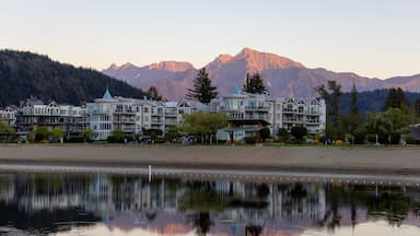 Um resort à beira-lago com águas refletoras, um cenário de montanhas e uma fileira de edifícios altos.