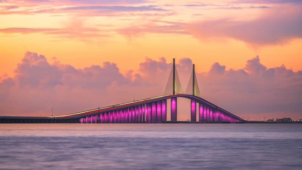 Uma ponte com duas torres imponentes e iluminação em cores de arco-íris.