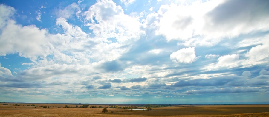 Um extenso campo aberto sob um céu parcialmente nublado.