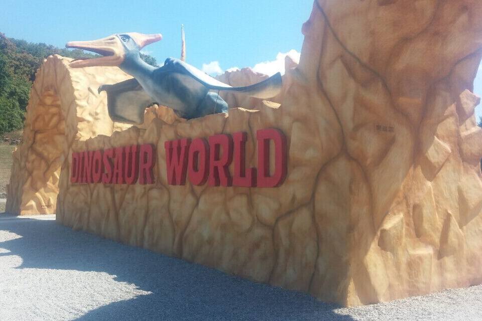 Entrada com tema de dinossauros, incluindo uma grande placa com a inscrição