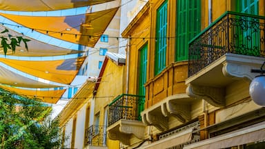 Um edifício com paredes amarelas, venezianas verdes e varandas decoradas.