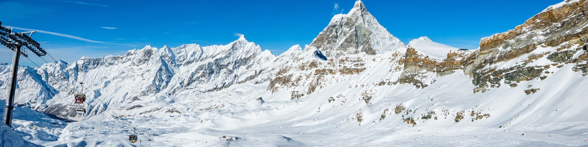 Cordilheira nevada com teleféricos e céu azul e límpido.