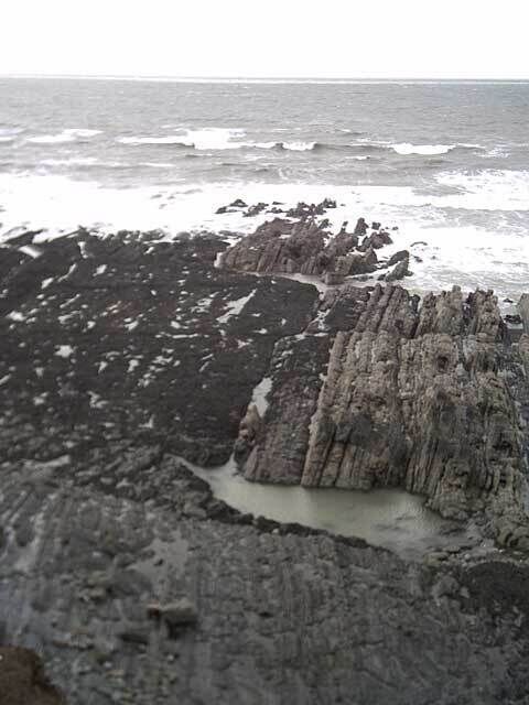 Litoral rochoso com falésias imponentes e um estreito canal.