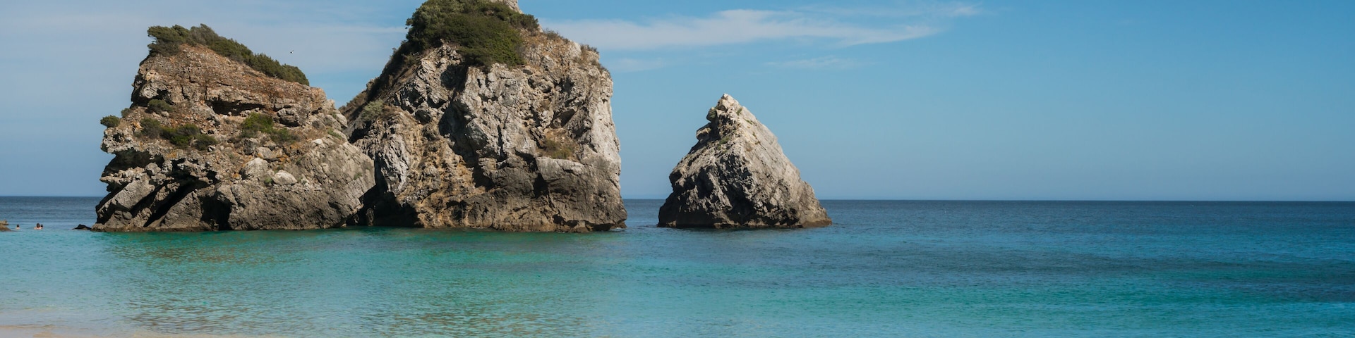Uma praia com formações rochosas e água turquesa cristalina.