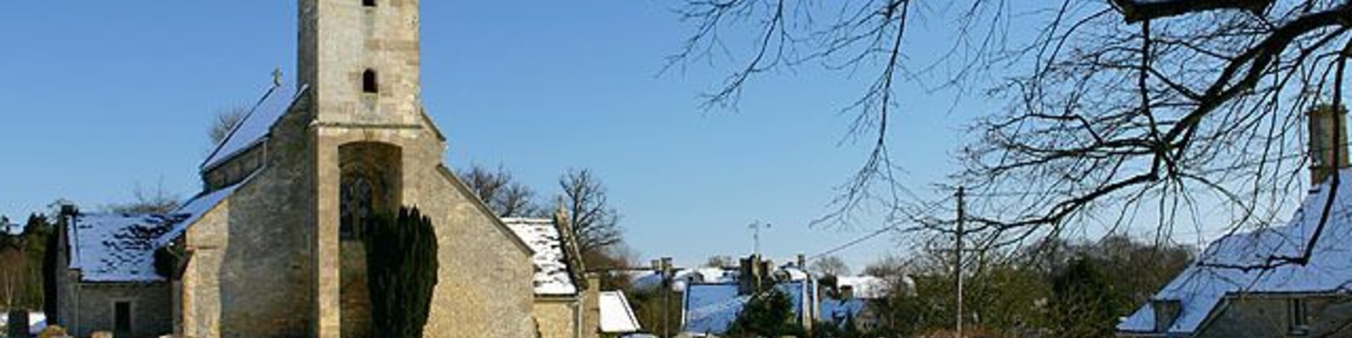 St Mary's parish church, Swinbrook, Oxfordshire, seen from the west in sun and snow