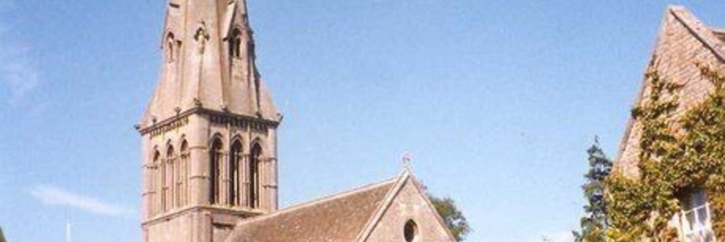 Igreja com uma torre alta e um muro de tijolos à frente.