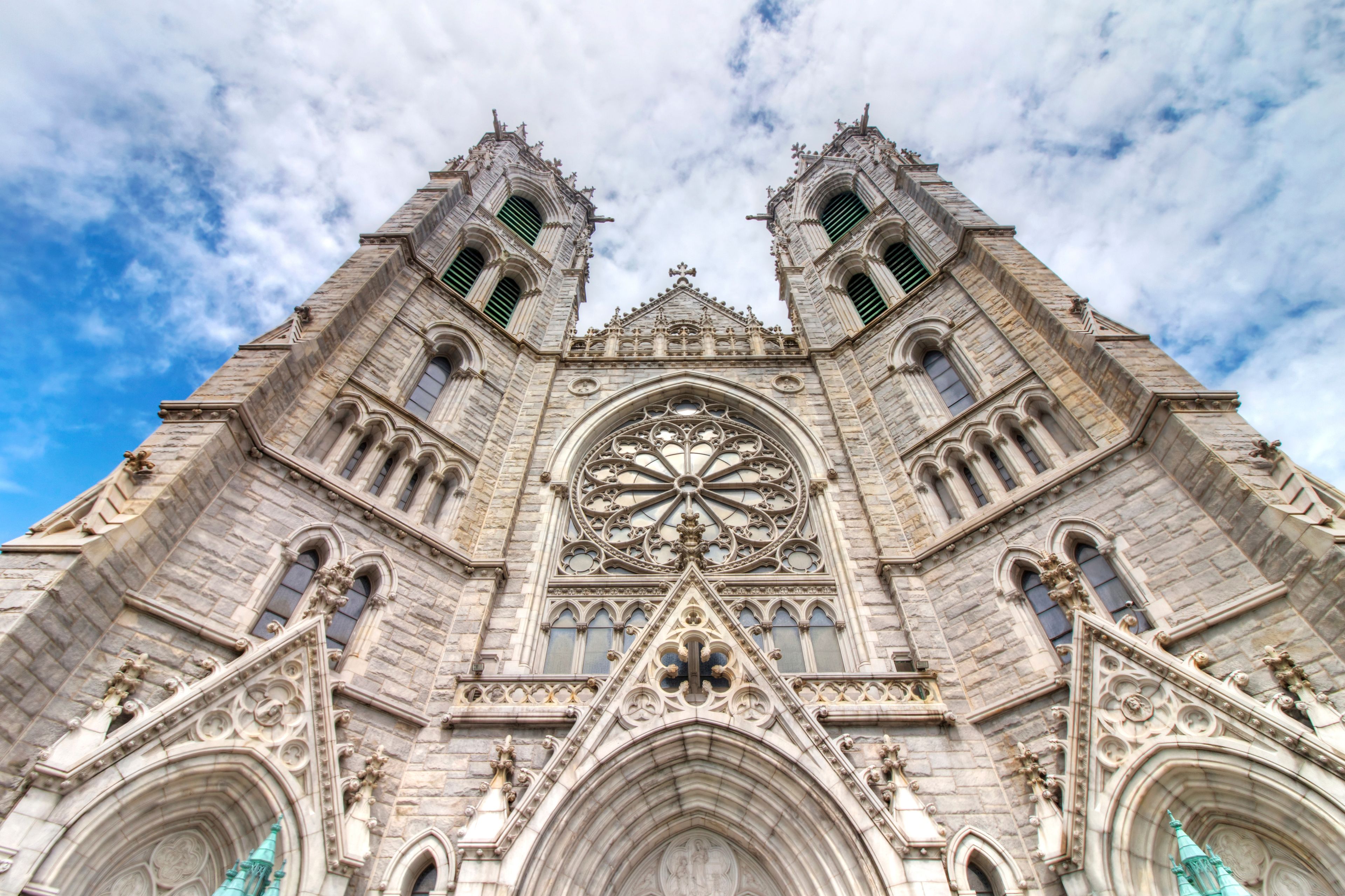 Uma catedral em estilo gótico com duas torres, esculturas de pedra elaboradas e um grande vitral de rosa.