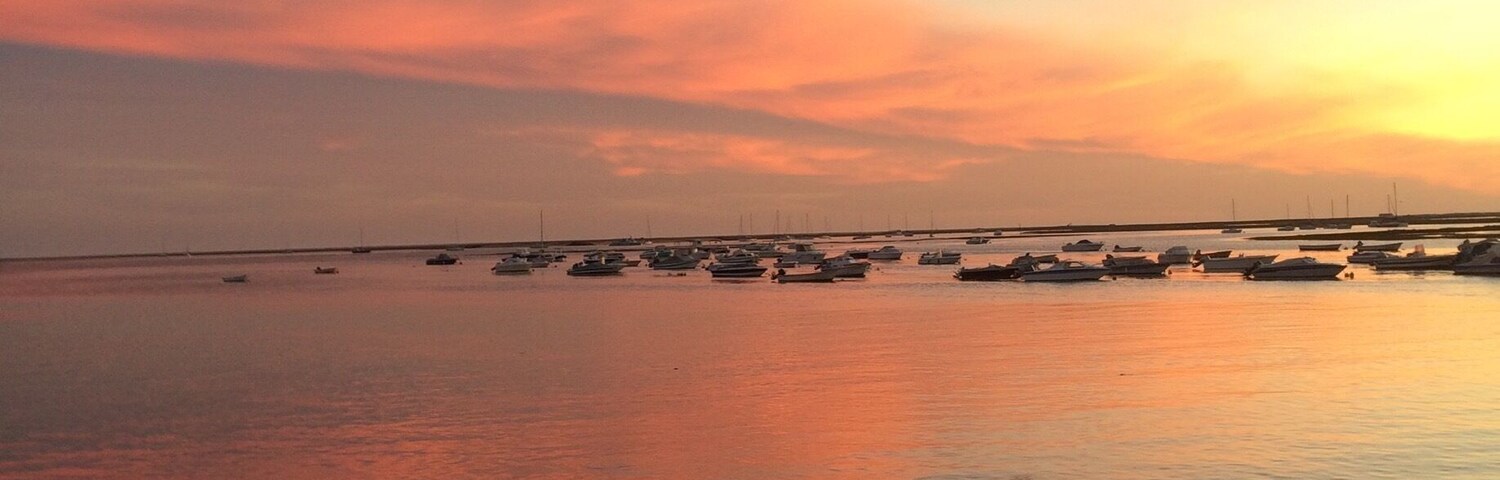 Mar calmo com barcos ao pôr do sol.